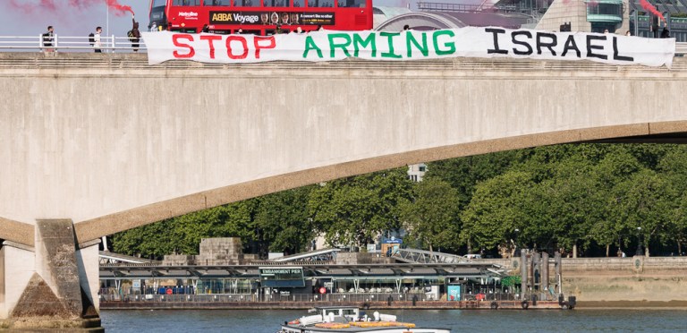 Protesters hang 80-foot banner reading “Stop Arming Israel” from ...